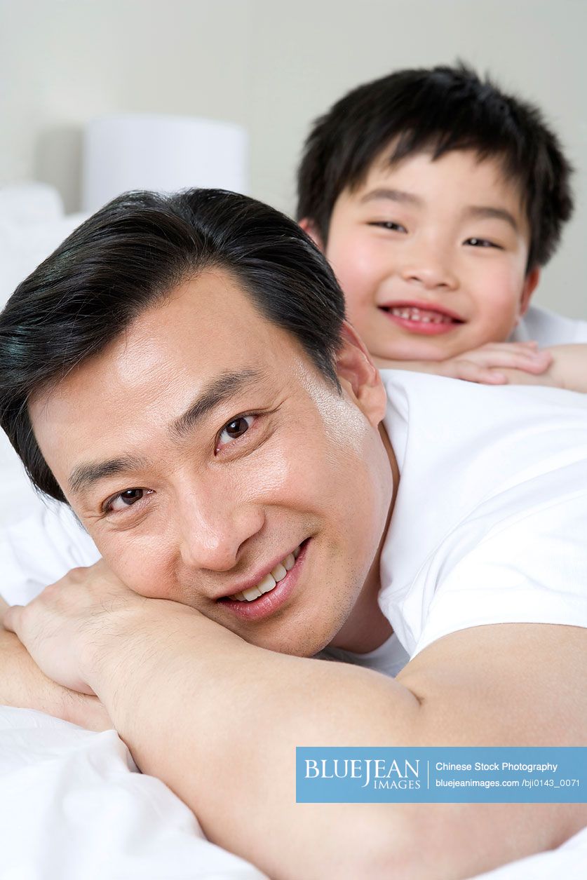 Chinese father and son smiling on bed-High-res stock photo for download