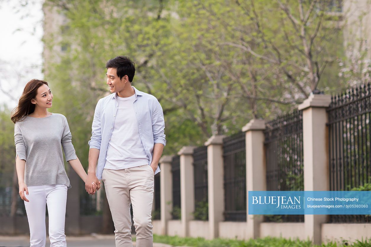 Happy young Chinese couple holding hands walking-High-res stock photo for download