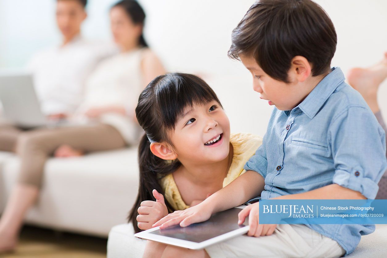 Happy young Chinese family using digital gadgets at home-High-res stock photo for download