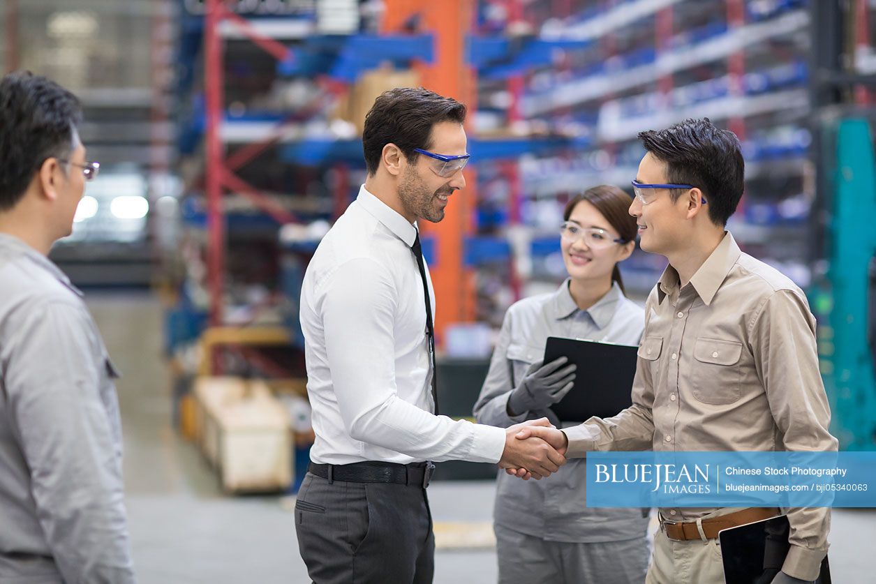 Businessman and engineer shaking hands in the factory-High-res stock photo for download
