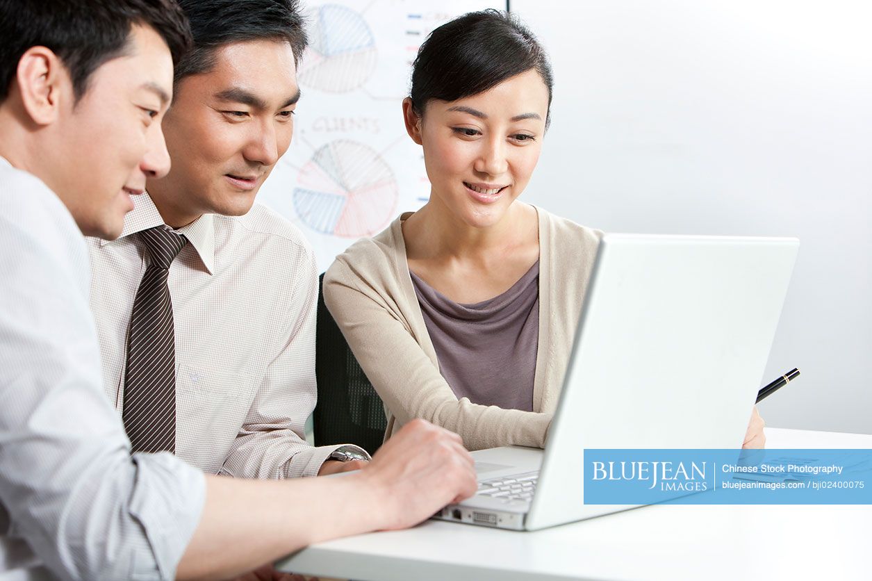 Chinese business executive showing younger businesspeople something on ...