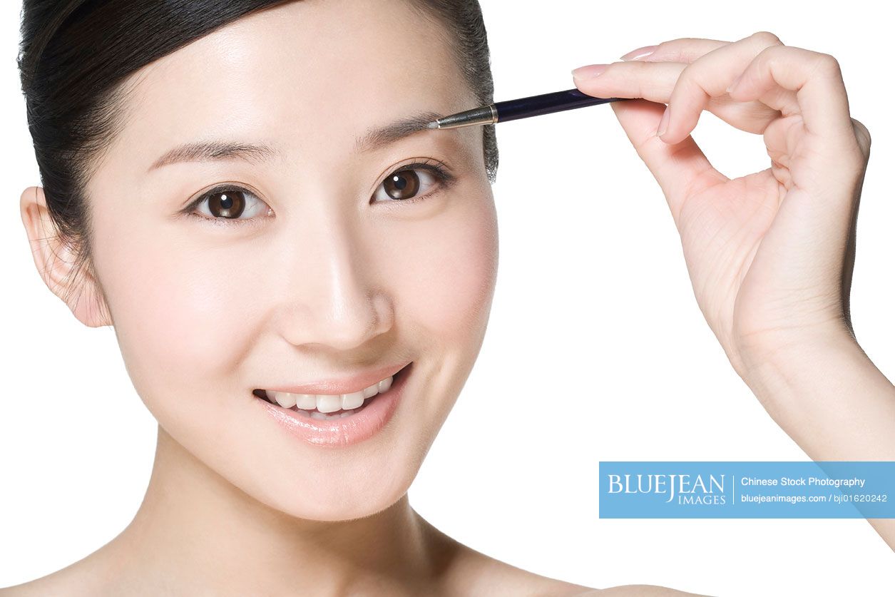 Beauty shot of a young Chinese woman penciling eyebrow-High-res stock ...