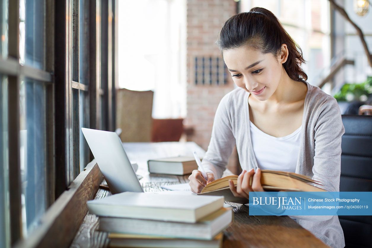 Young Chinese woman studying in cafe-High-res stock photo for download
