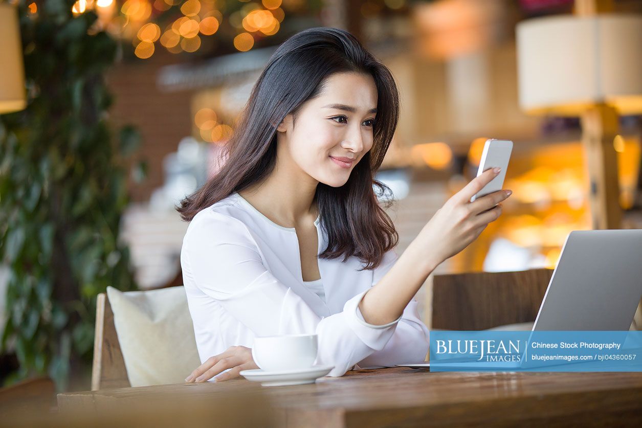 Young Chinese woman using smart phone in cafe-High-res stock photo for ...