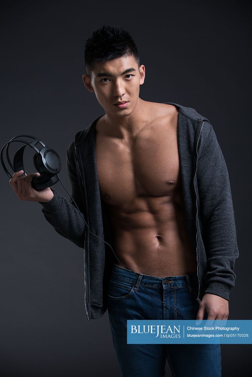 Young Chinese muscular man holding a headphone-High-res stock photo for download