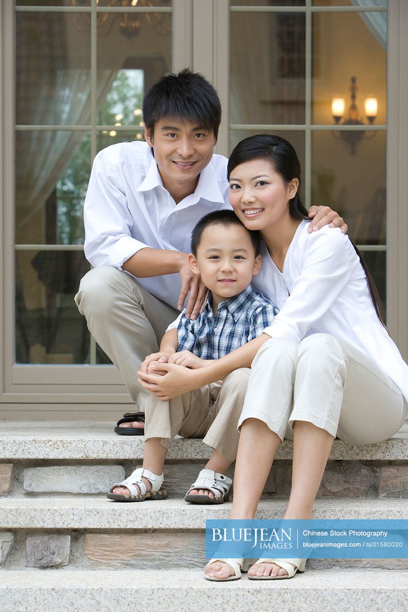 A Chinese family of three sitting in front of a house-High-res stock ...