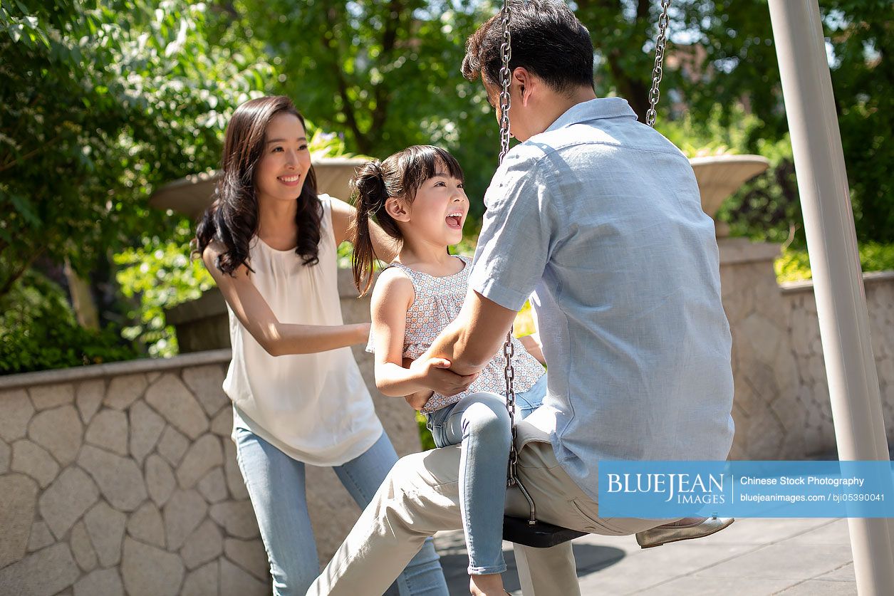 Happy young Chinese family playing on swing-High-res stock photo for download