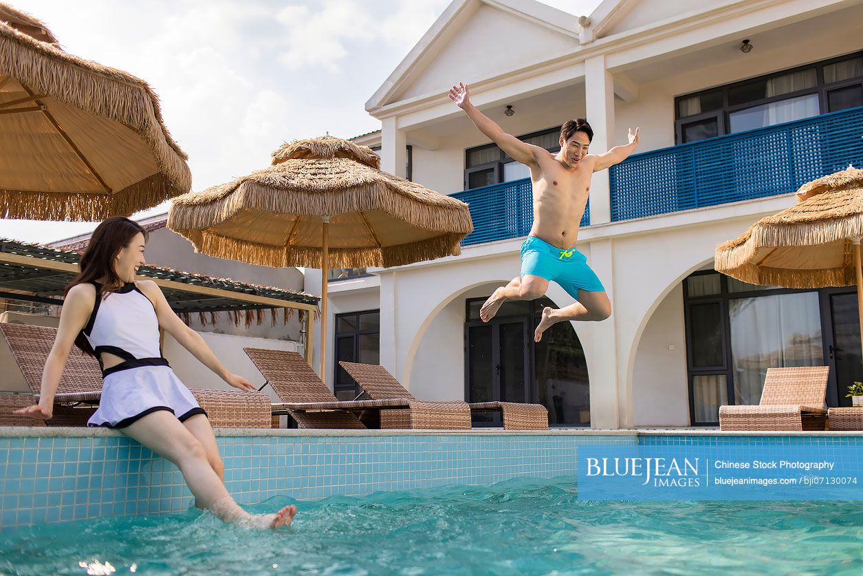 Happy young Chinese couple jumping into swimming pool-High-res stock ...
