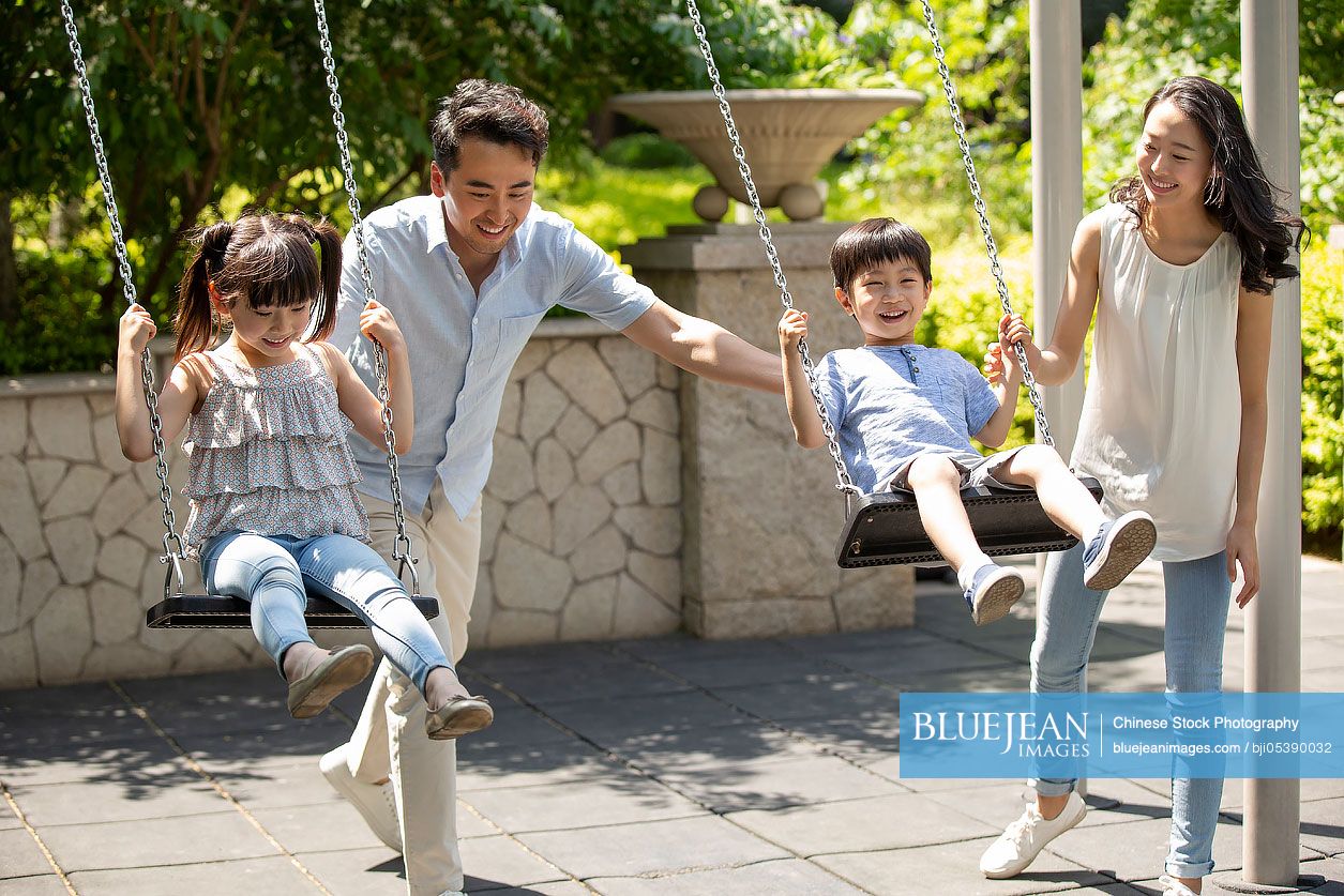 Happy young Chinese family playing on swings-High-res stock photo for ...