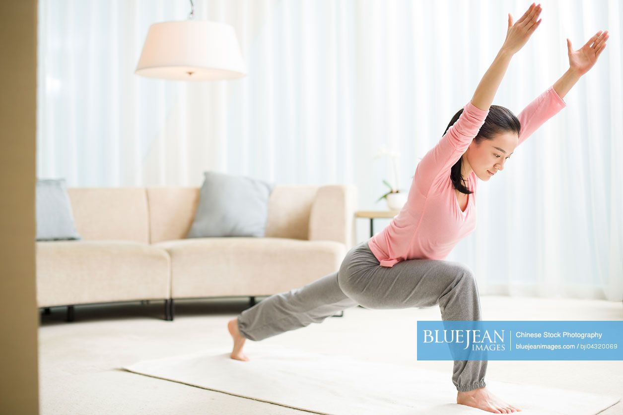 Young Chinese woman practicing yoga in living room-High-res stock photo for download