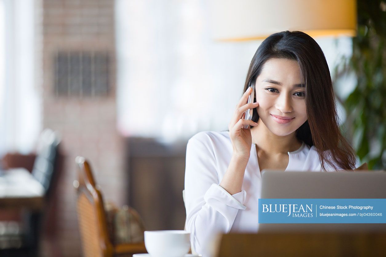 Young Chinese woman talking on phone in cafe-High-res stock photo for ...