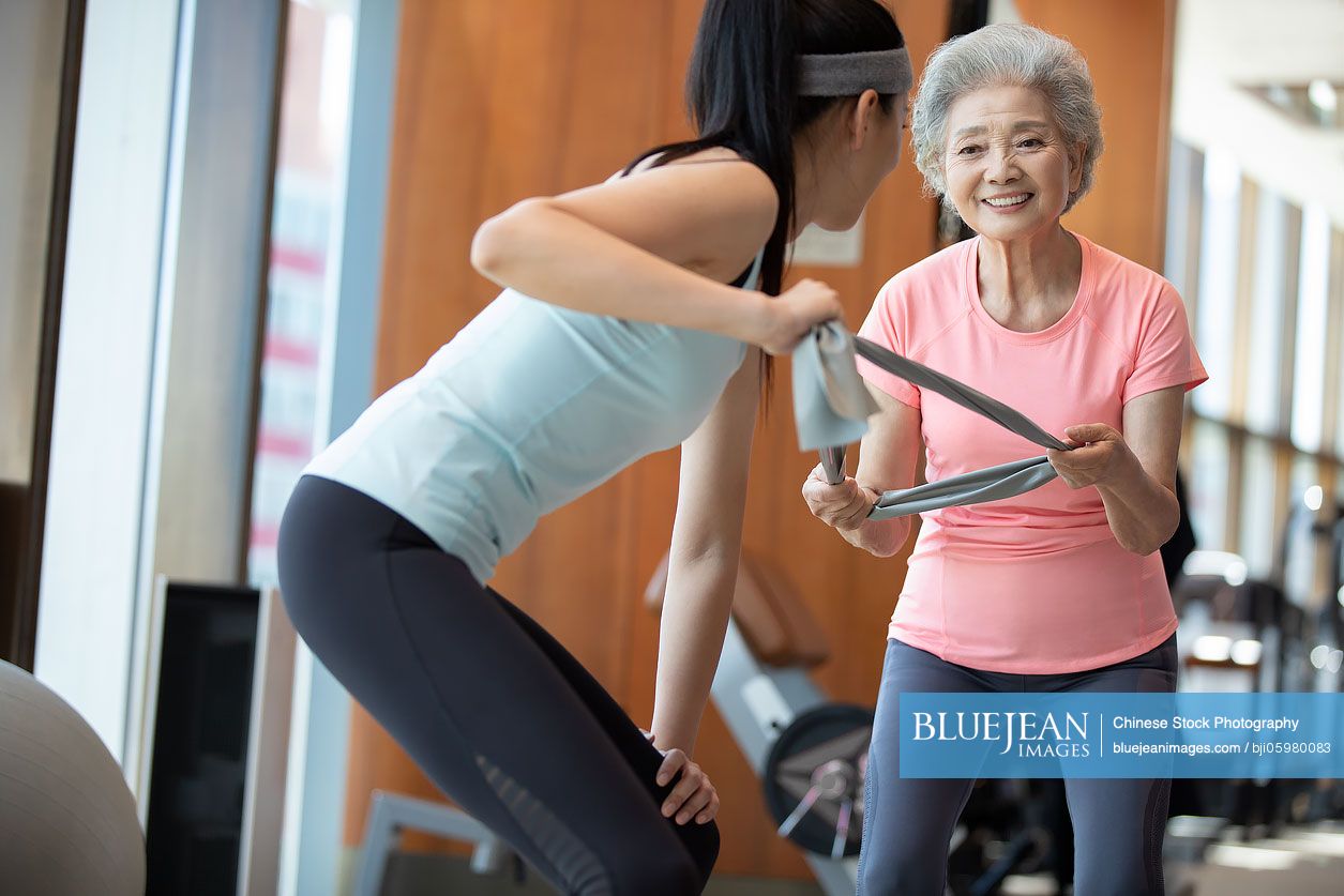 Senior Chinese woman working out with personal trainer at gym-High-res ...