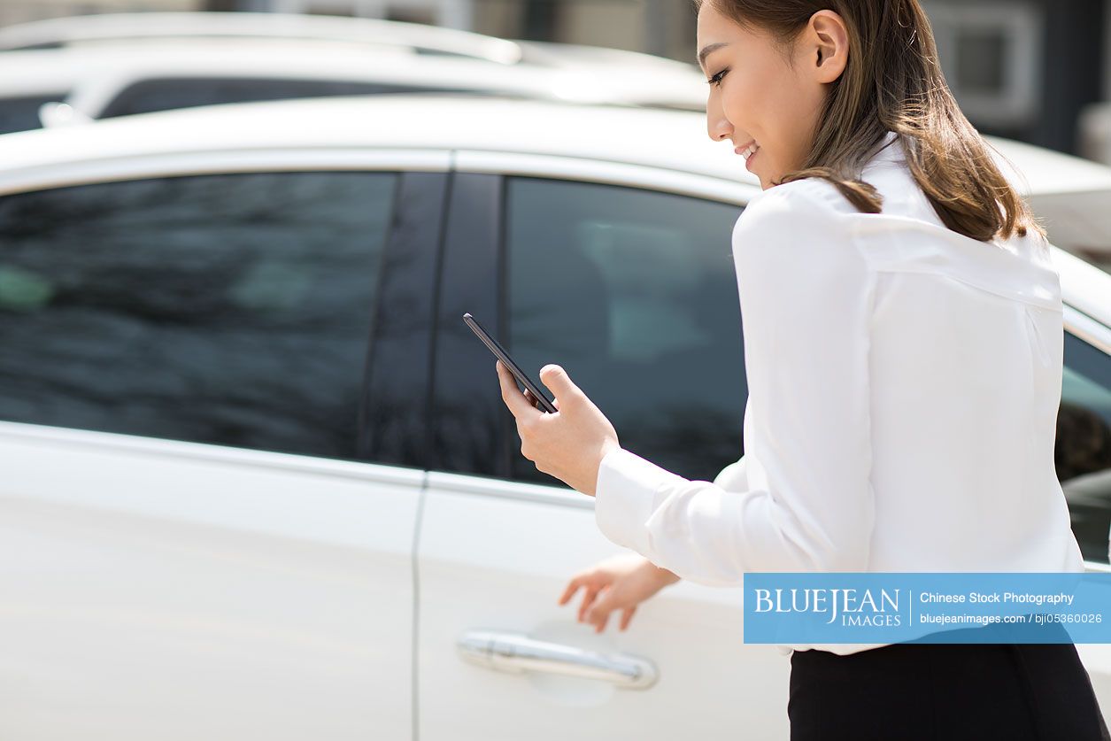 Young Chinese businesswoman opening car door-High-res stock photo for download