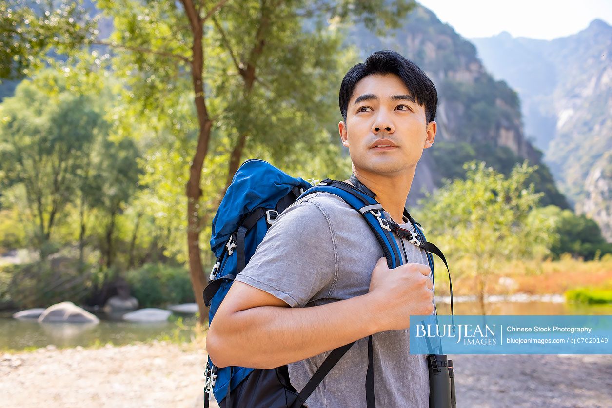 Young Chinese man hiking outdoors-High-res stock photo for download