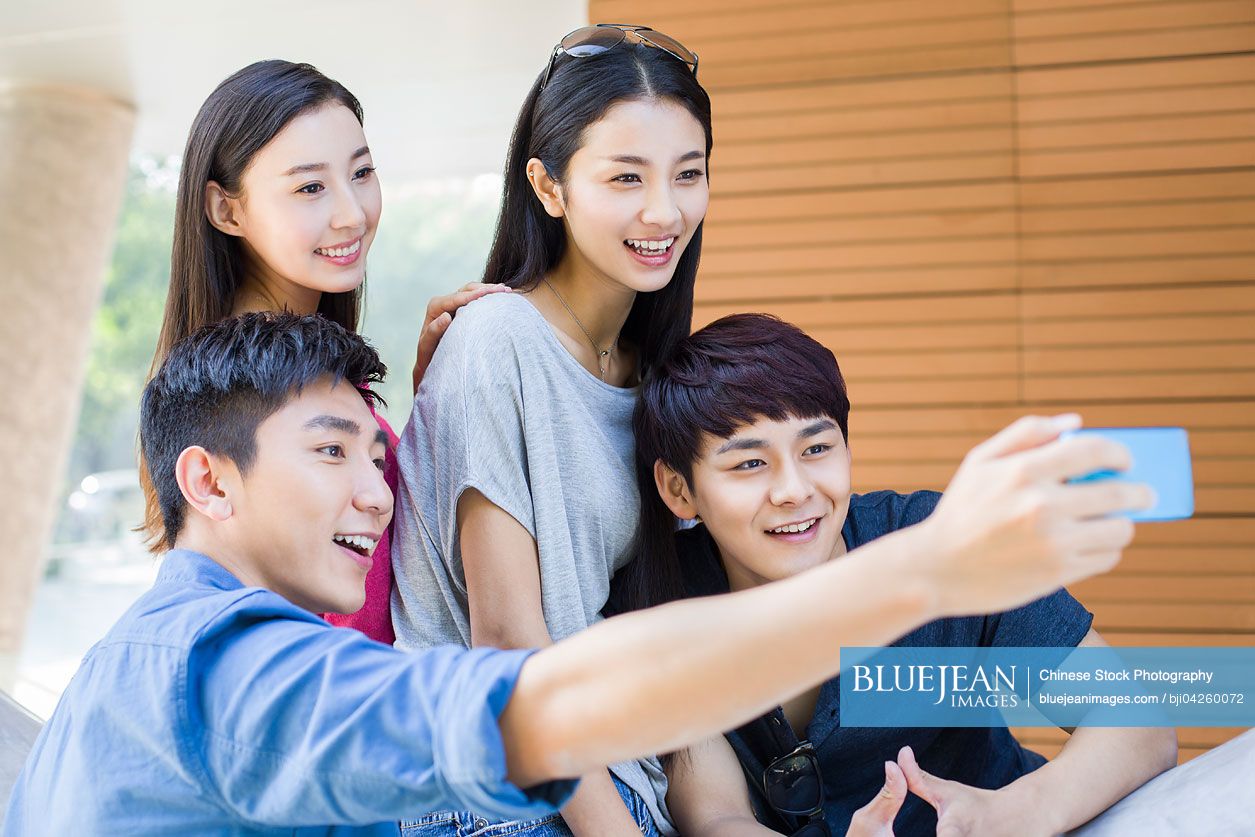 Young Chinese friends taking self portrait with a smart phone-High-res ...