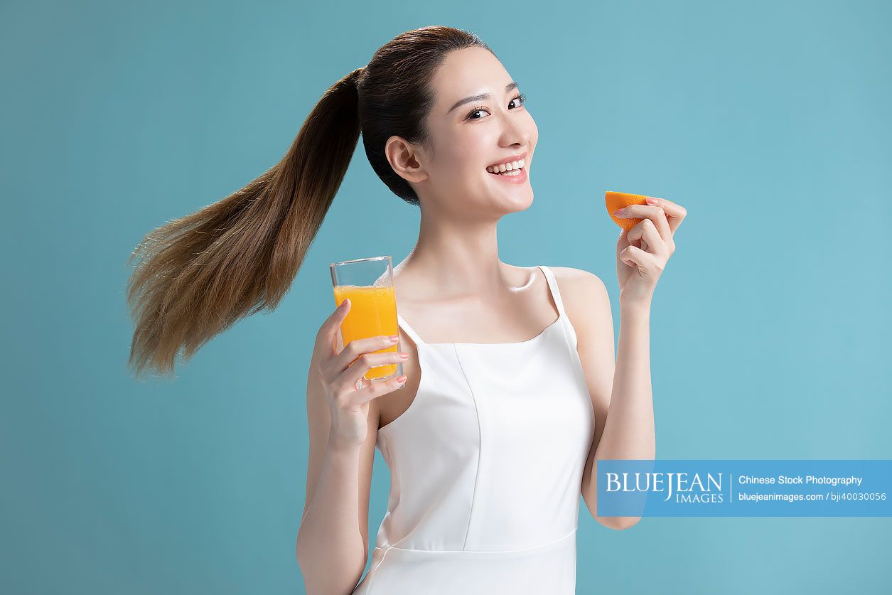 Beautiful young Chinese woman drinking orange juice-High-res stock ...