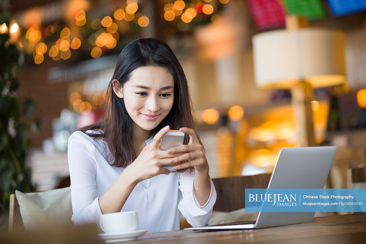 Young Chinese woman using smart phone in cafe-High-res stock photo for ...