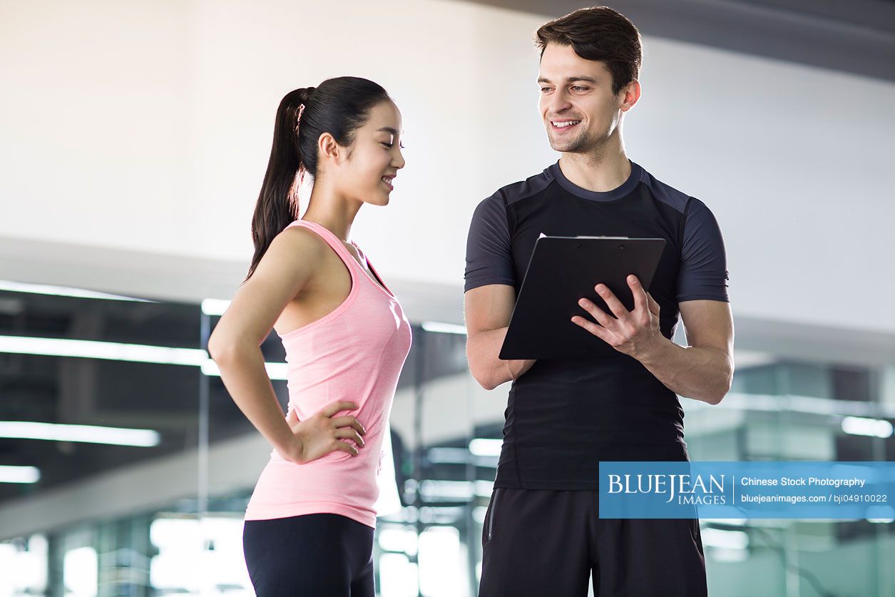 Young Chinese woman talking with trainer at gym-High-res stock photo for download