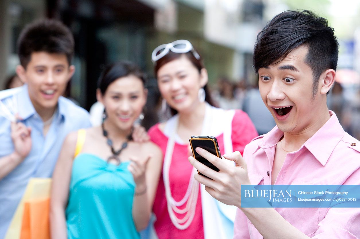 Young Chinese man using phone in front of friends-High-res stock photo ...
