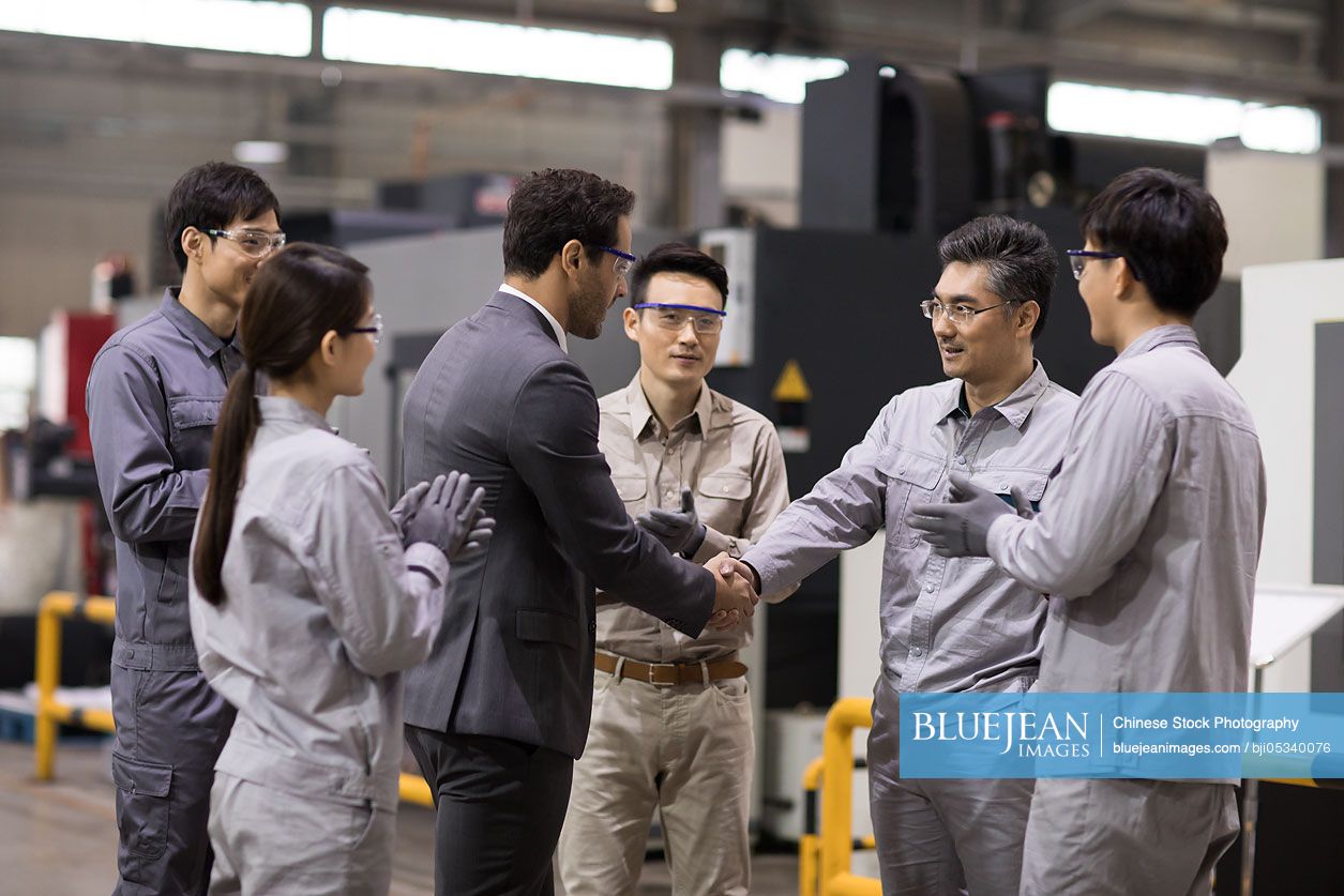 Businessman and engineer shaking hands in the factory-High-res stock photo for download