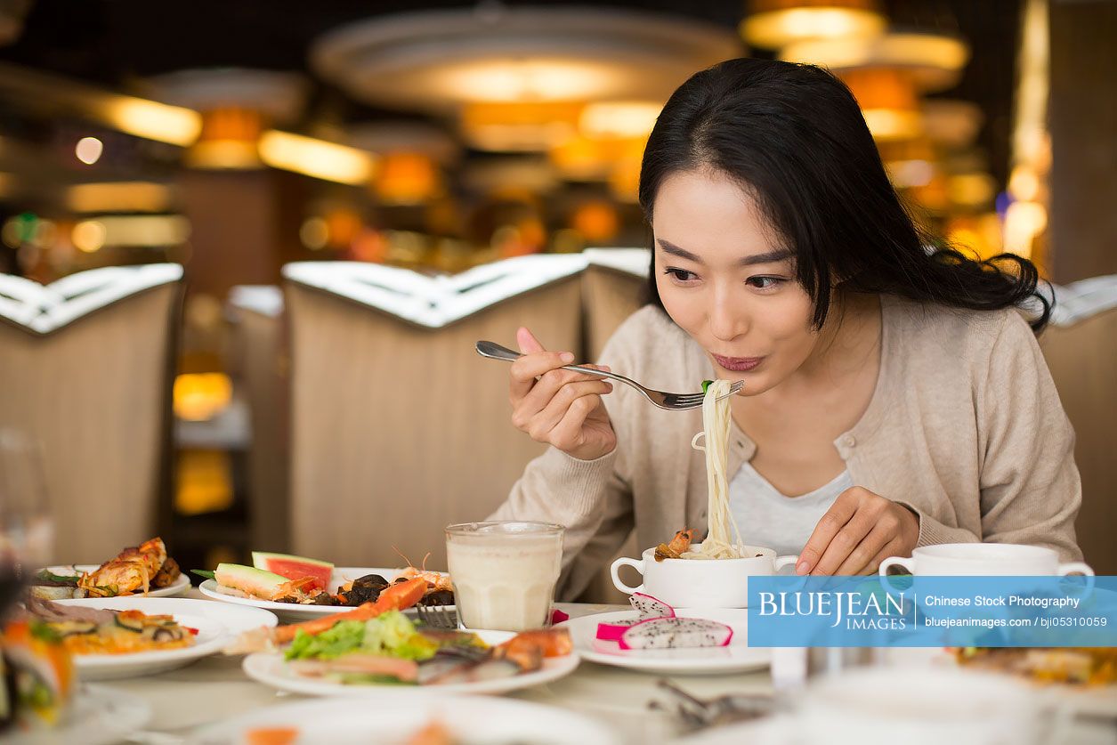 Cheerful young Chinese woman having buffet dinner-High-res stock photo ...