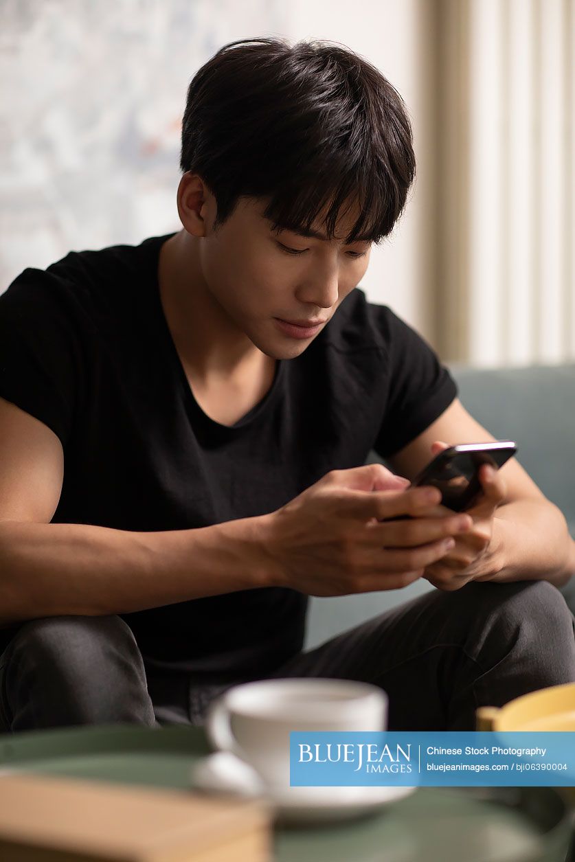Young Chinese man using smartphone at home-High-res stock photo for ...