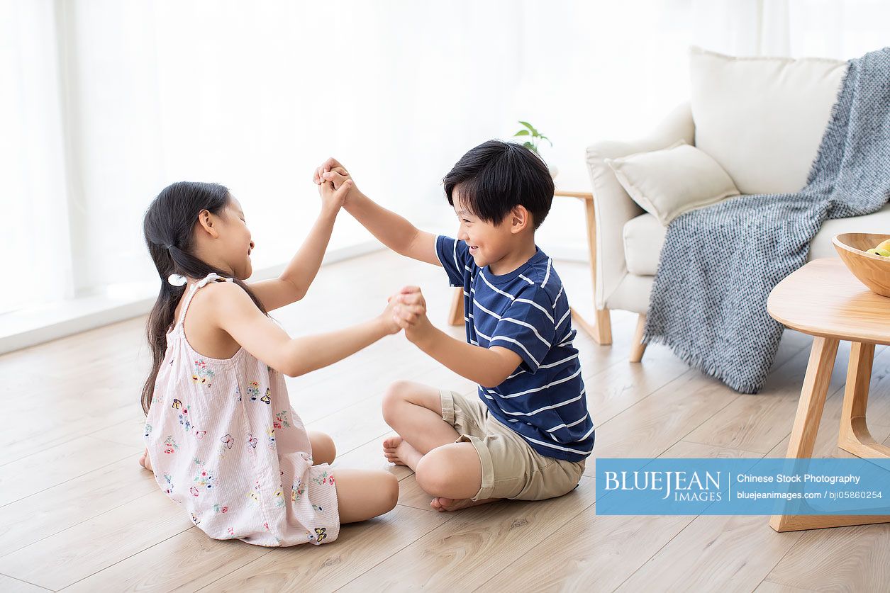 Happy Chinese sibling playing in living room-High-res stock photo for ...