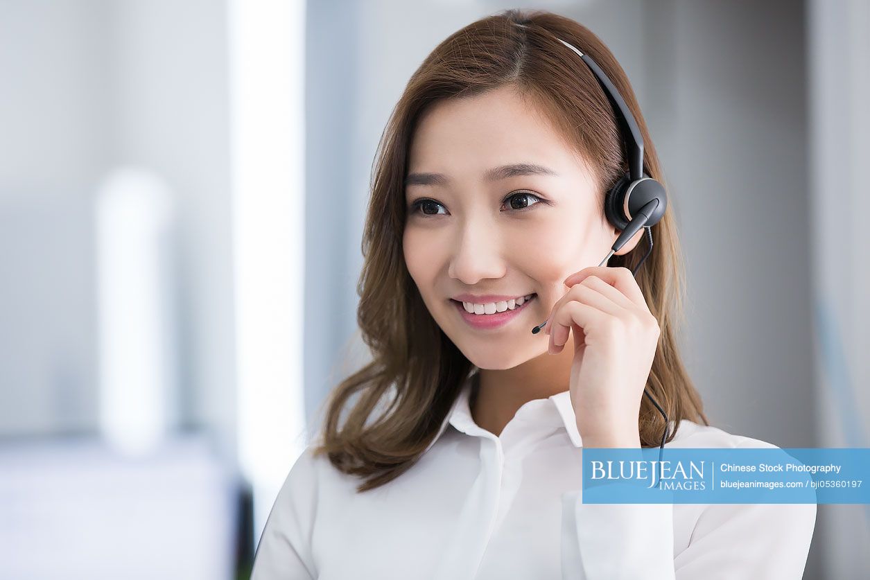 Cheerful young Chinese businesswoman with headset in office-High-res ...