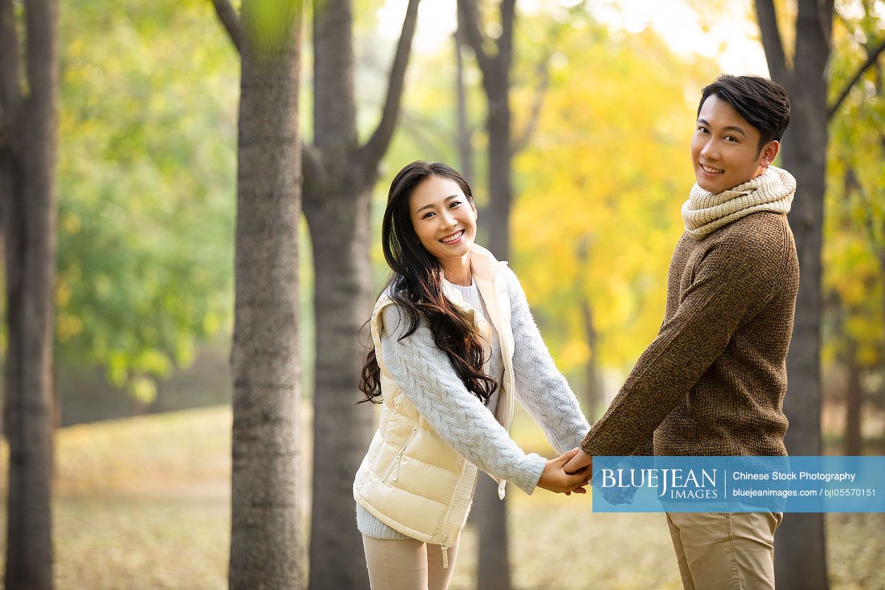 Happy young Chinese couple holding hands in woods-High-res stock photo for download