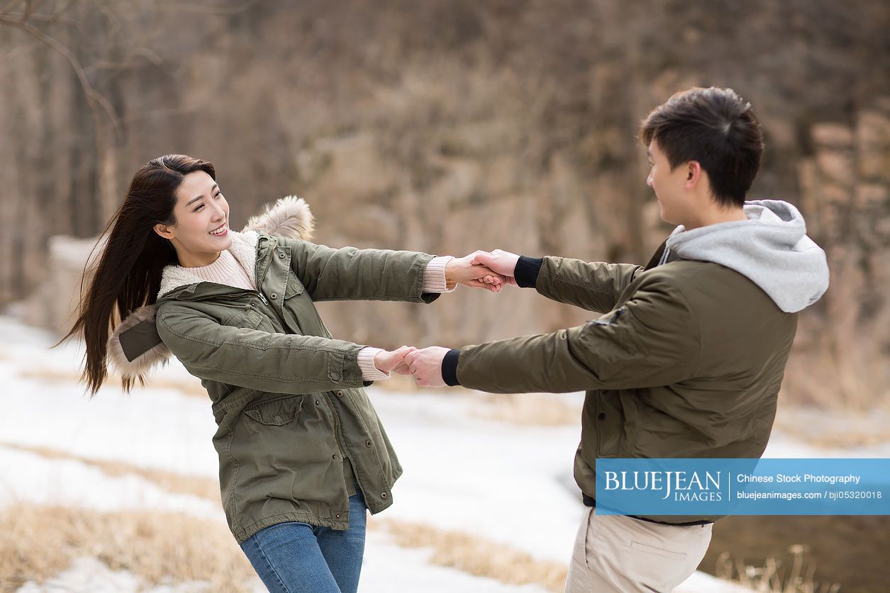 Happy young Chinese couple holding hands spinning-High-res stock photo for download