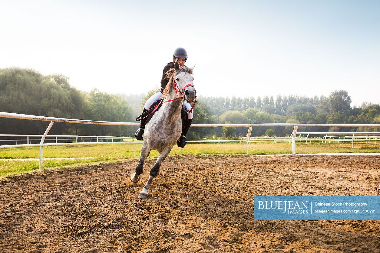 Cheerful young Chinese woman riding horse-High-res stock photo for download
