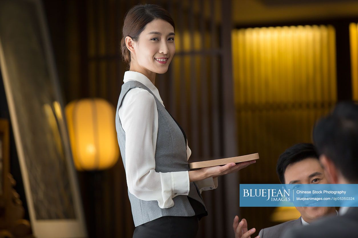 Elegant Chinese waitress holding a tray-High-res stock photo for download