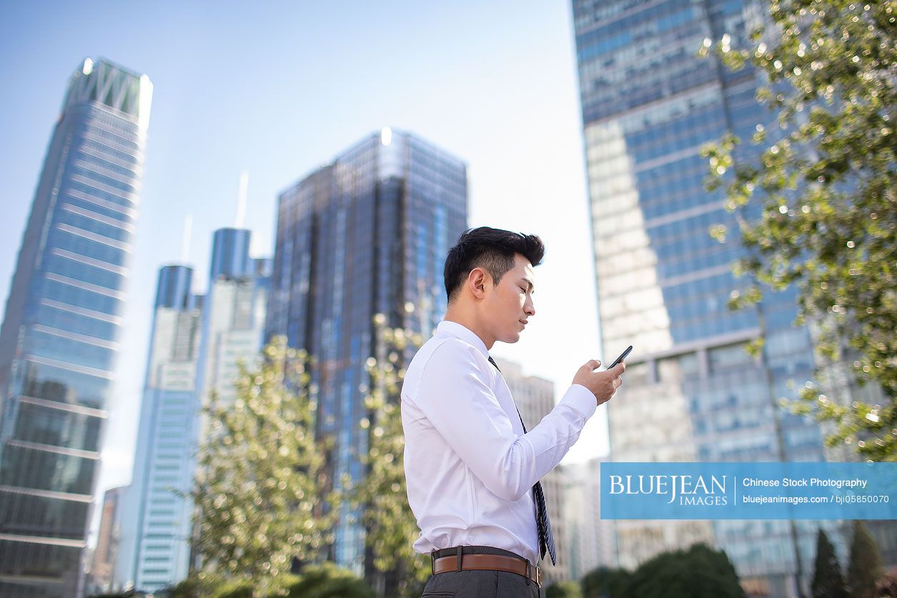 Confident young Chinese businessman using smart phone-High-res stock ...