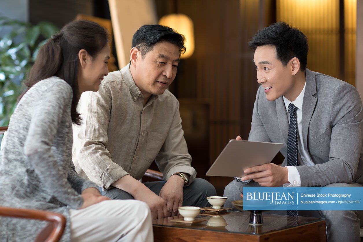 Confident Chinese financial consultant talking with mature couple-High ...