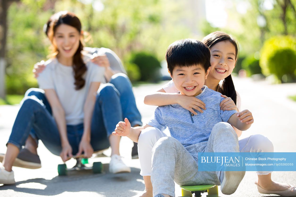 Happy young Chinese family playing with skateboards-High-res stock photo for download