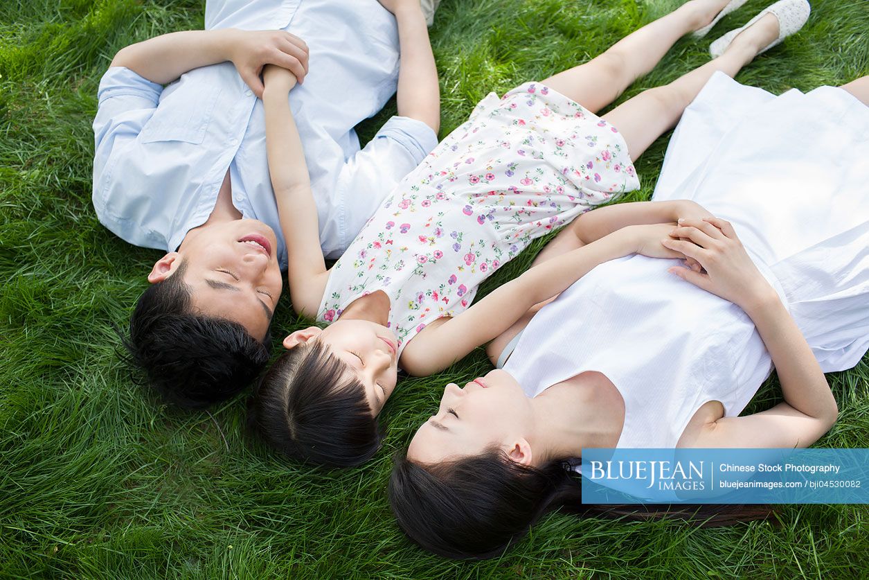 Happy young Chinese family lying on grass-High-res stock photo for download