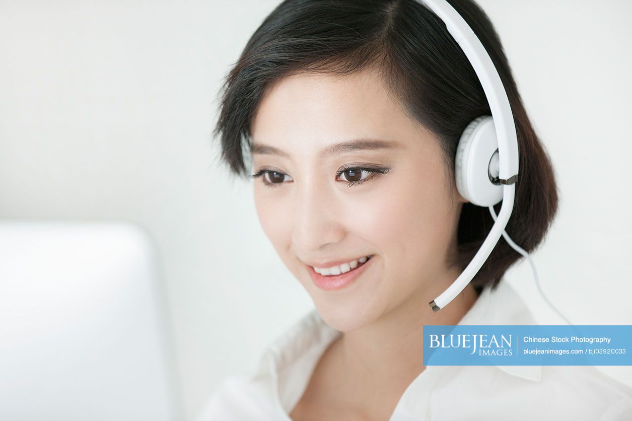 Cheerful Chinese businesswoman with headset in office-High-res stock photo for download