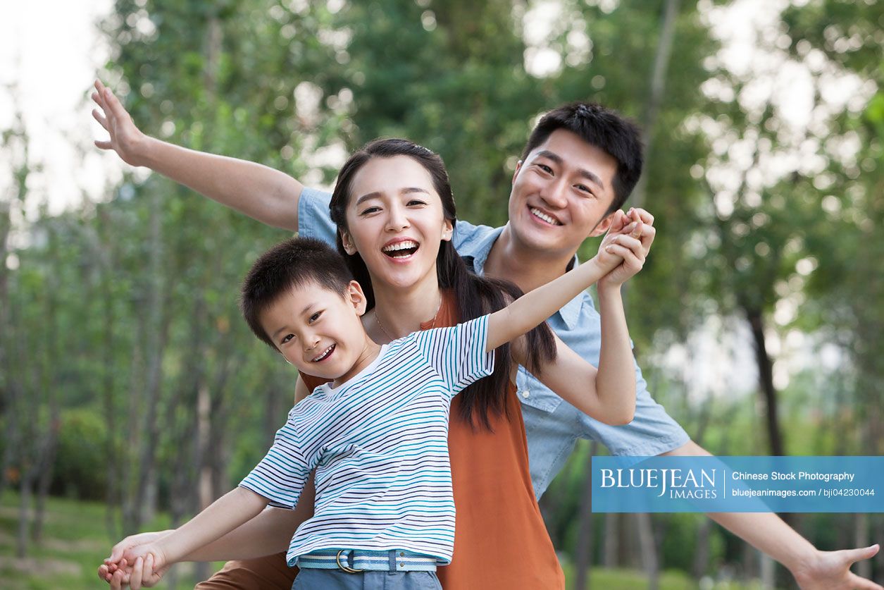 Portrait of happy young Chinese family with arms outstretched-High-res ...