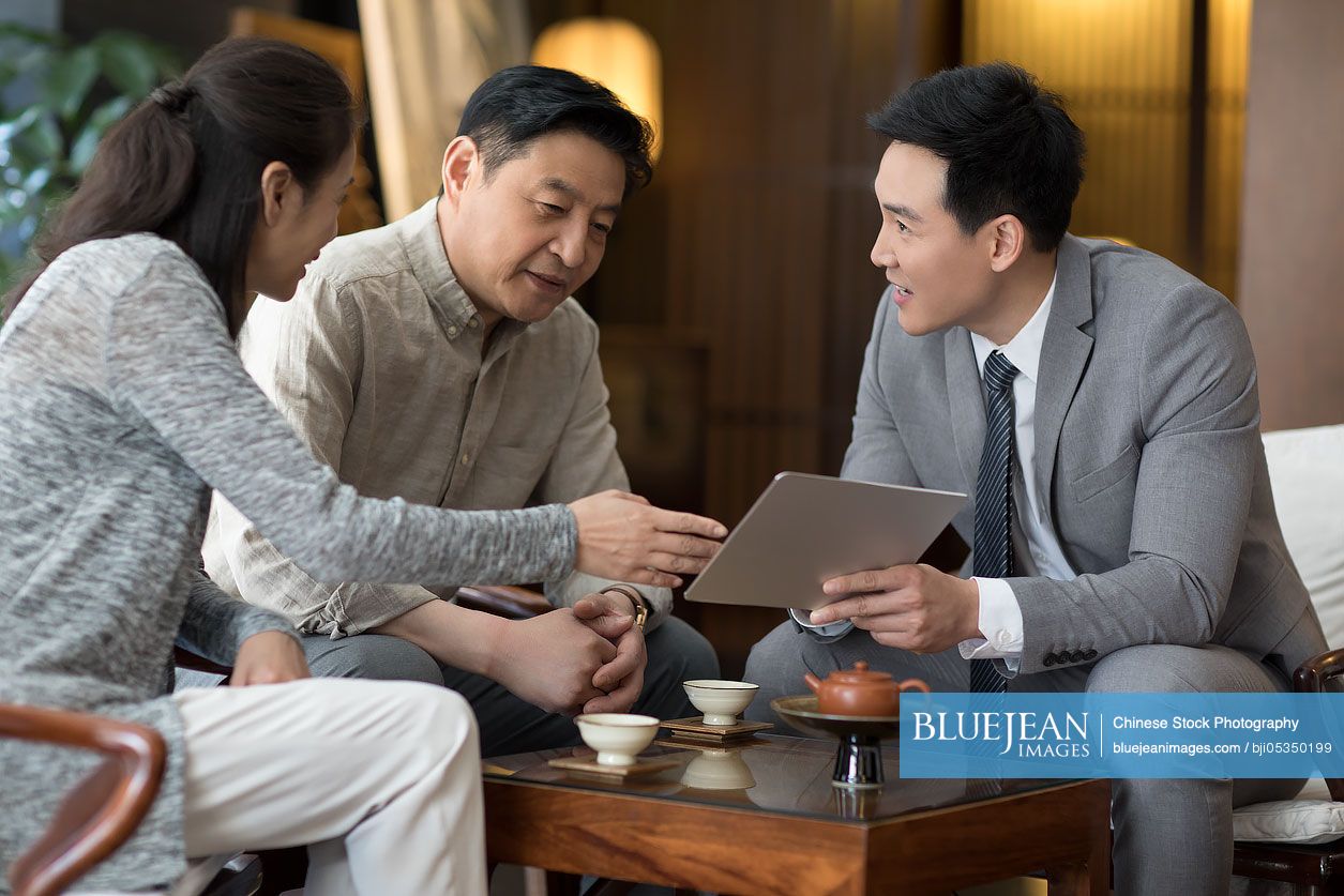 Confident Chinese financial consultant talking with mature couple-High ...
