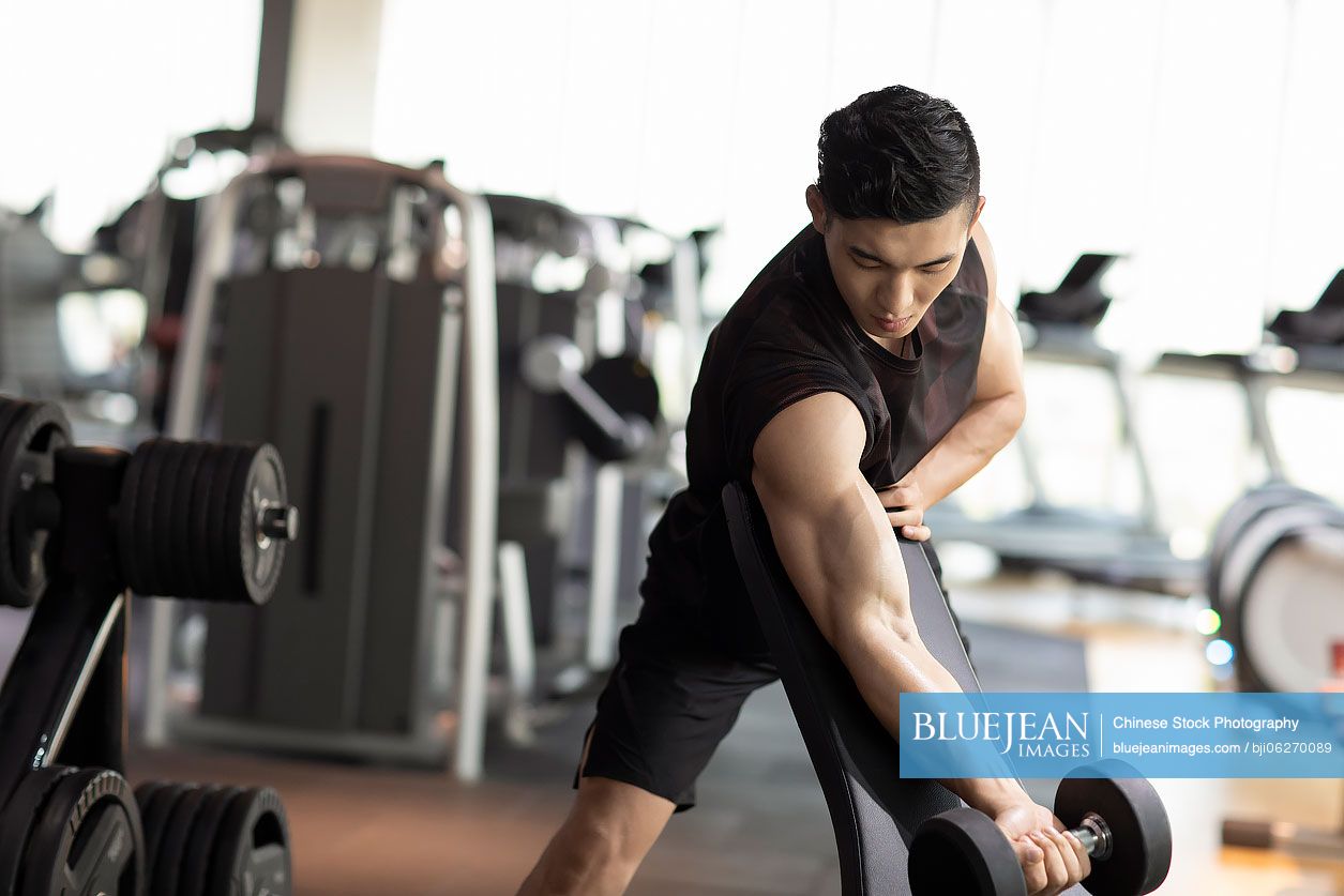 Young Chinese man working out with dumbbell at gym-High-res stock photo ...