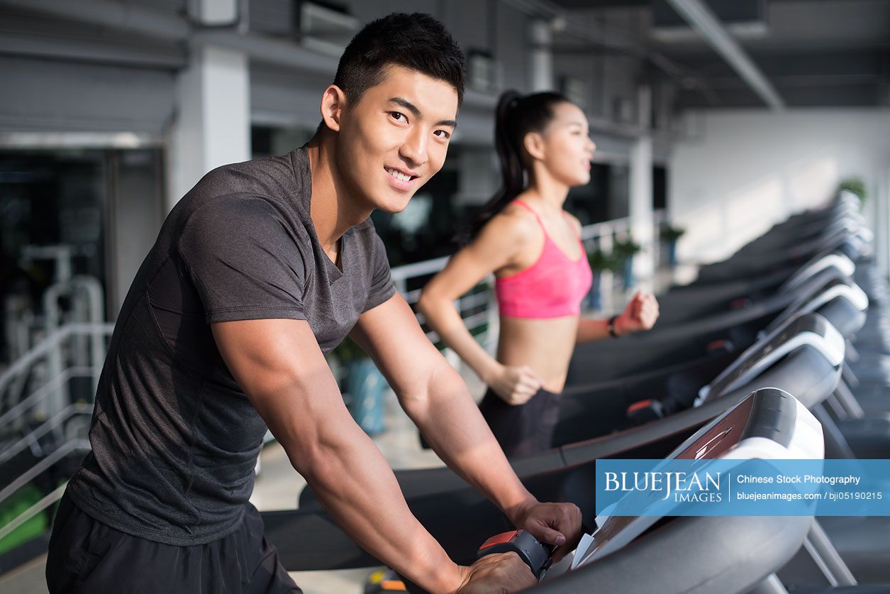 Young Chinese couple exercising on treadmills in gym-High-res stock photo for download
