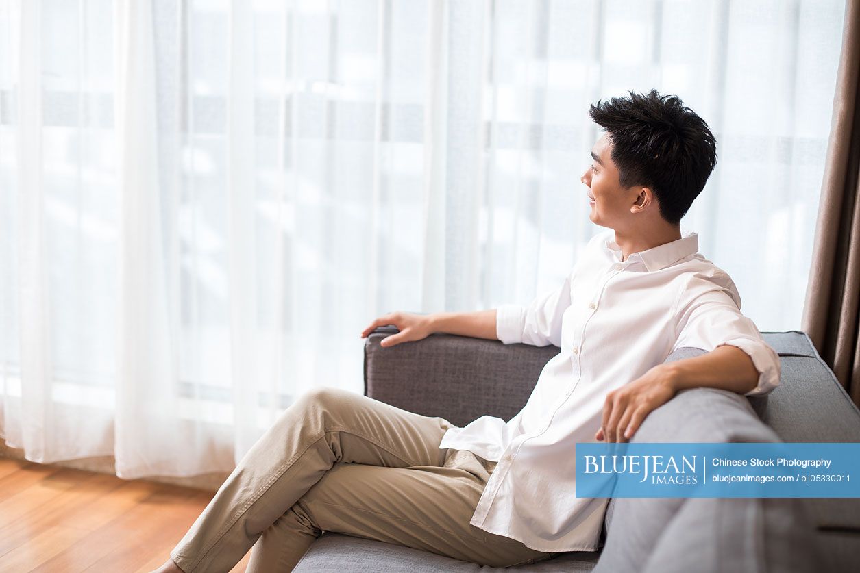 Young Chinese man relaxing on sofa-High-res stock photo for download