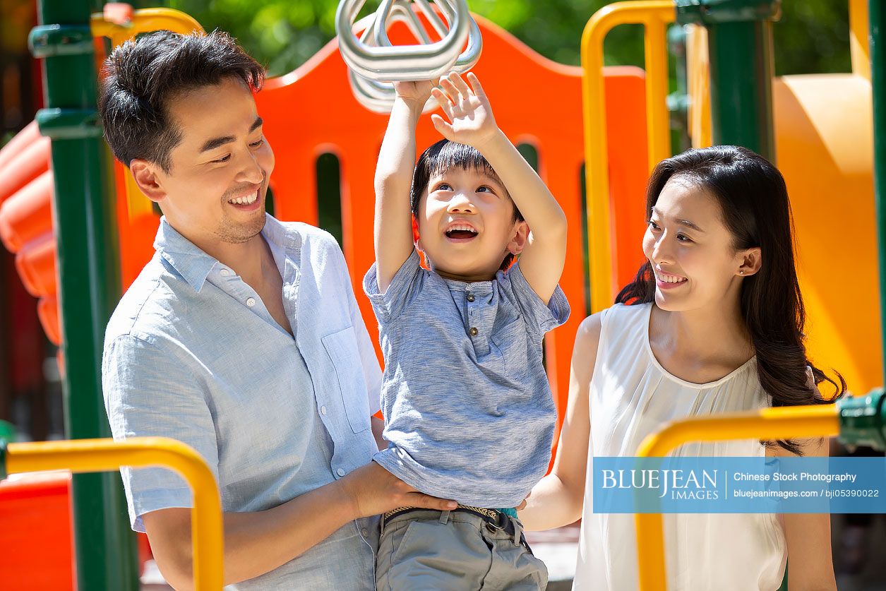 Happy young Chinese family playing in amusement park-High-res stock photo for download