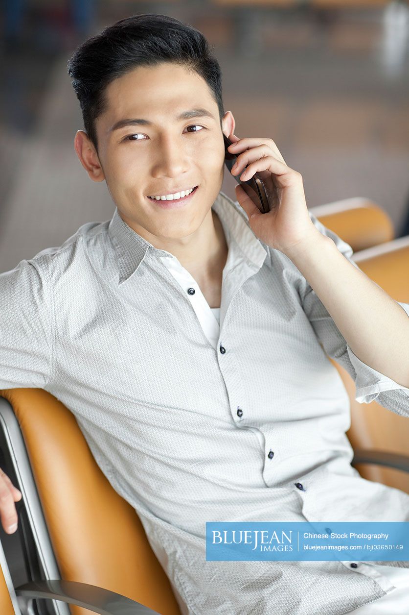 Young Chinese man talking on the phone in airport lounge-High-res stock ...