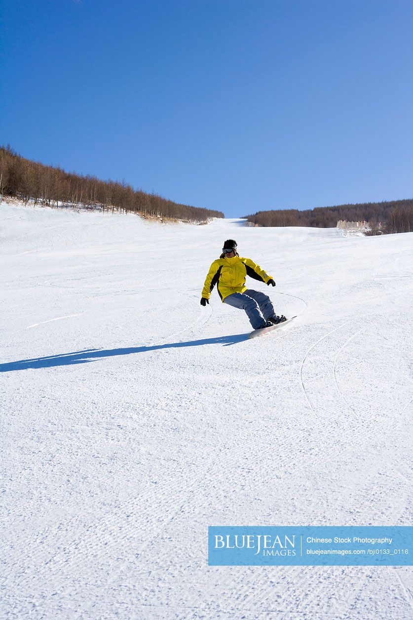 Young Chinese man snowboarding-High-res stock photo for download