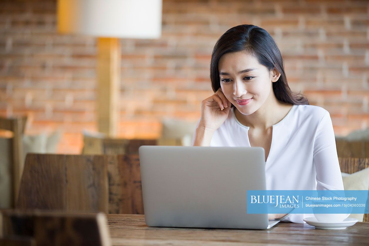 Young Chinese woman using laptop in cafe-High-res stock photo for download