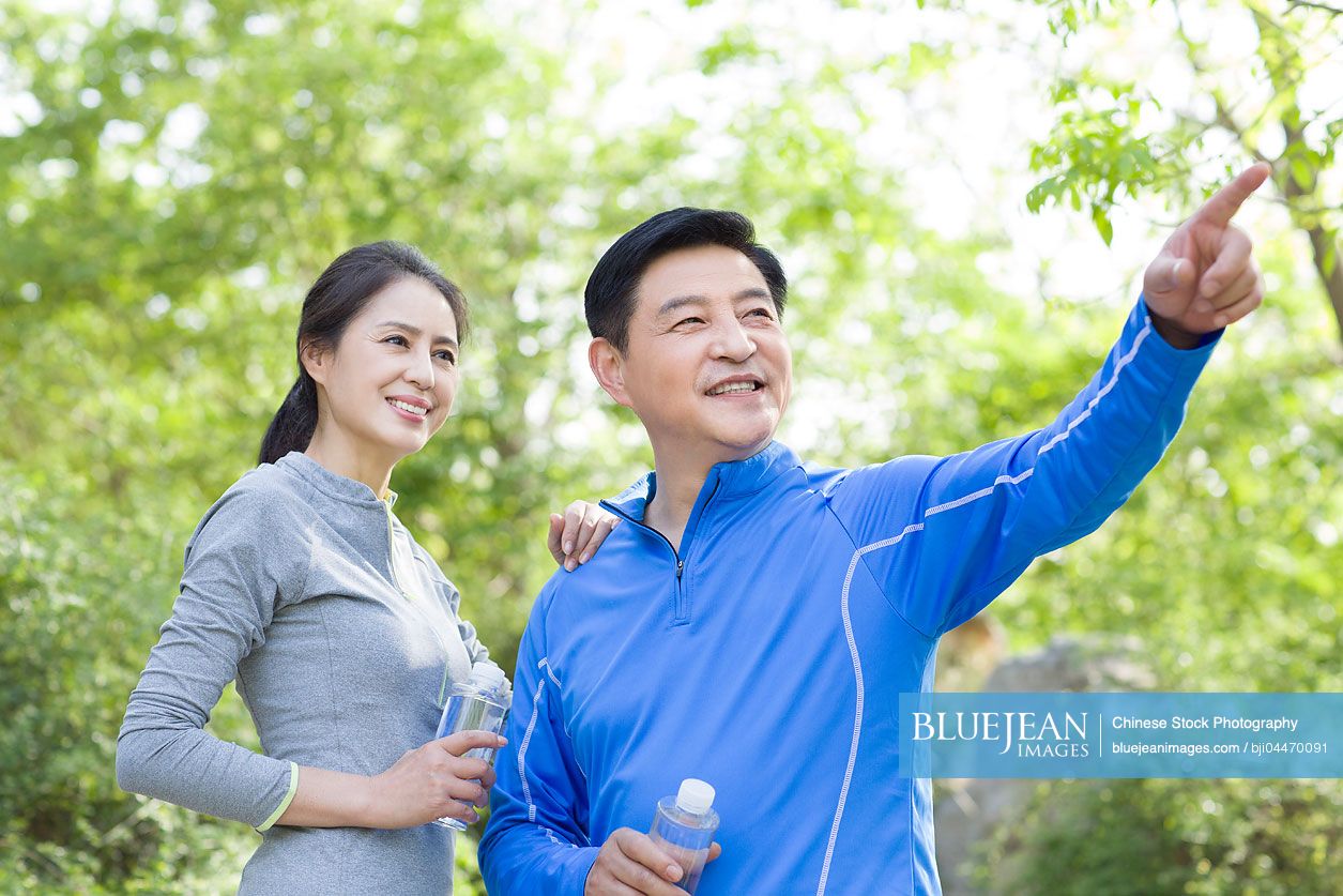 Happy mature Chinese couple holding bottled water after exercising-High-res stock photo for download