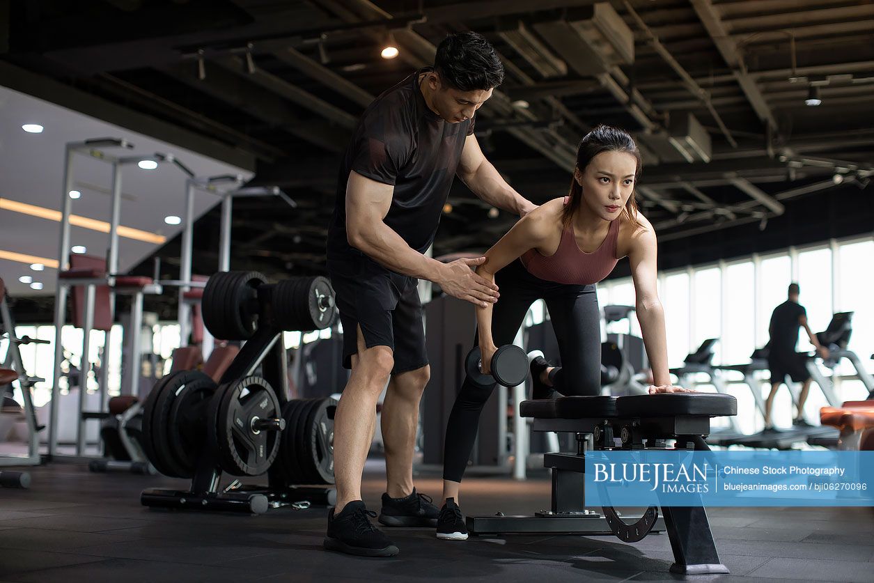 Young Chinese woman working out with personal trainer at gym-High-res ...