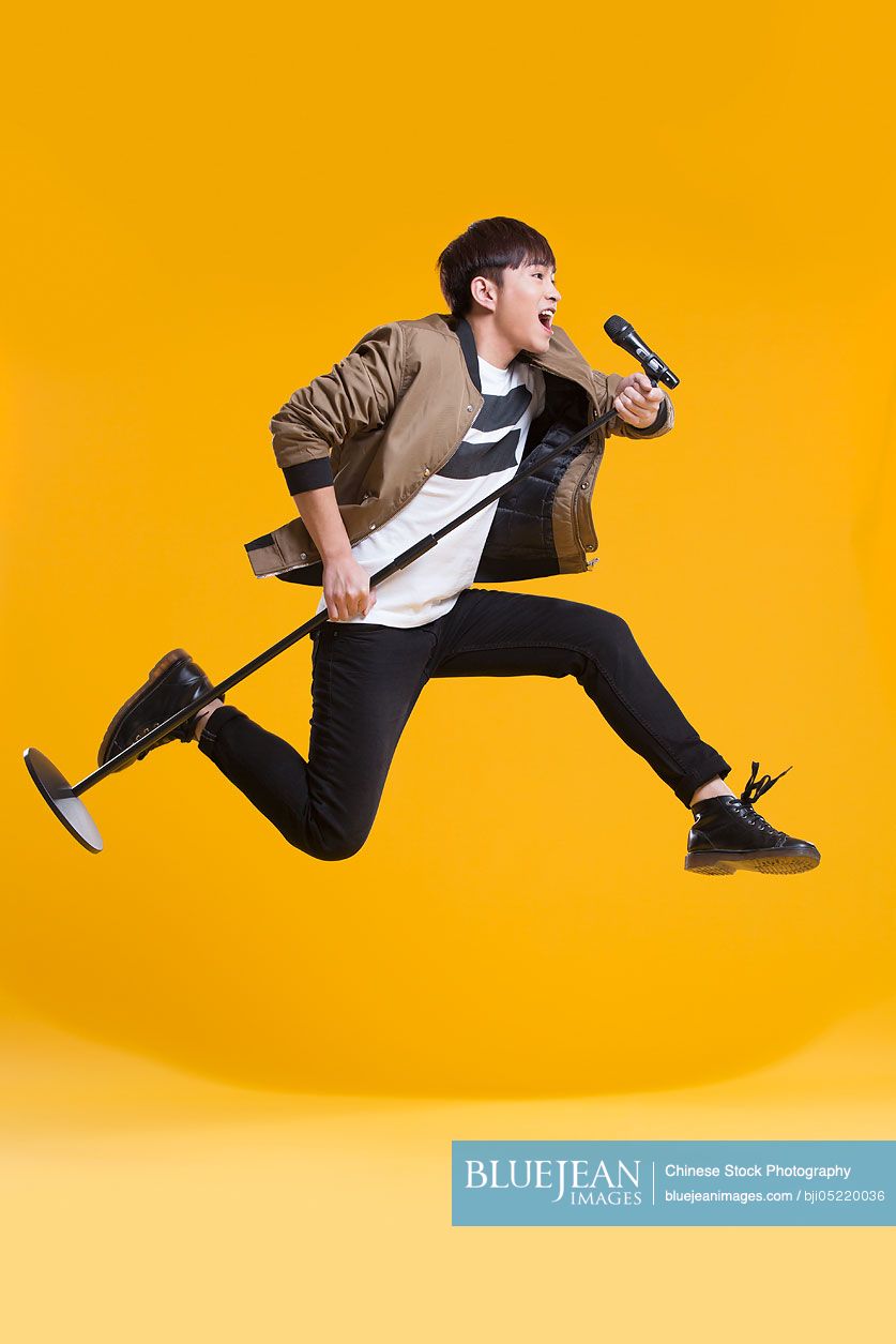 Cheerful young Chinese man singing with microphone-High-res stock photo for download