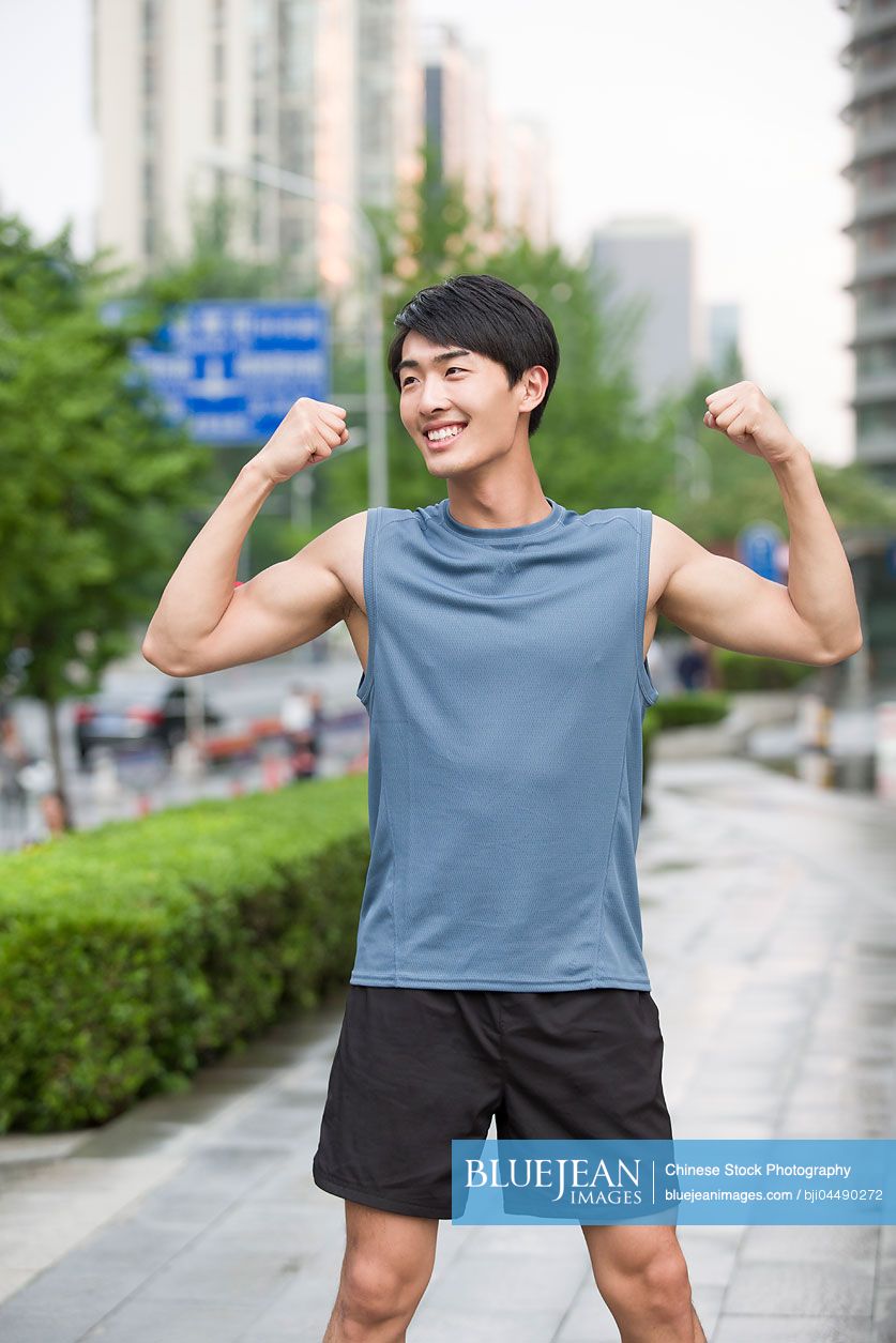 Young Chinese man flexing his muscles-High-res stock photo for download